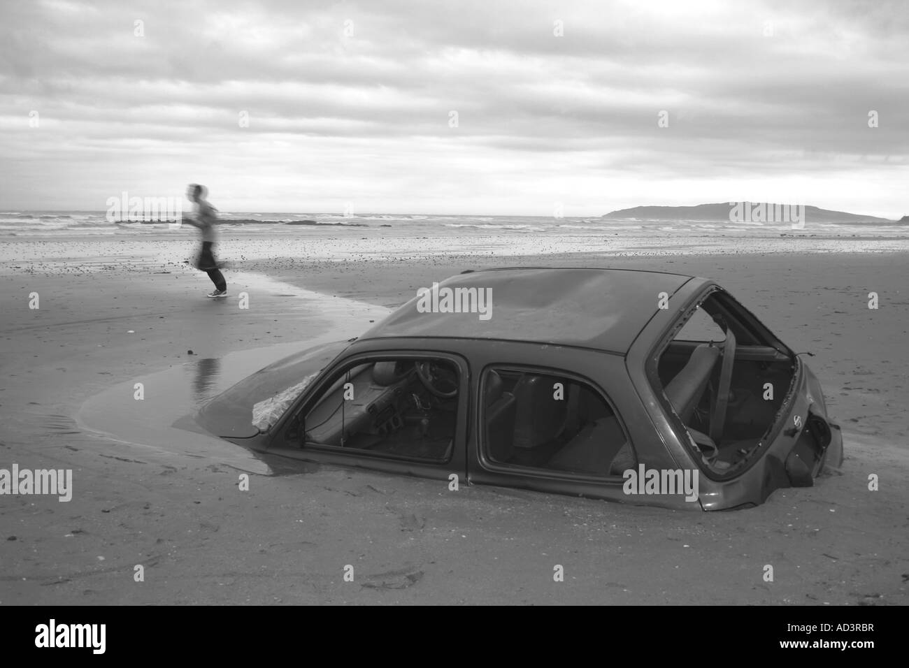 Jogger and stranded car on beach at Rush, County Dublin, Republic of ...