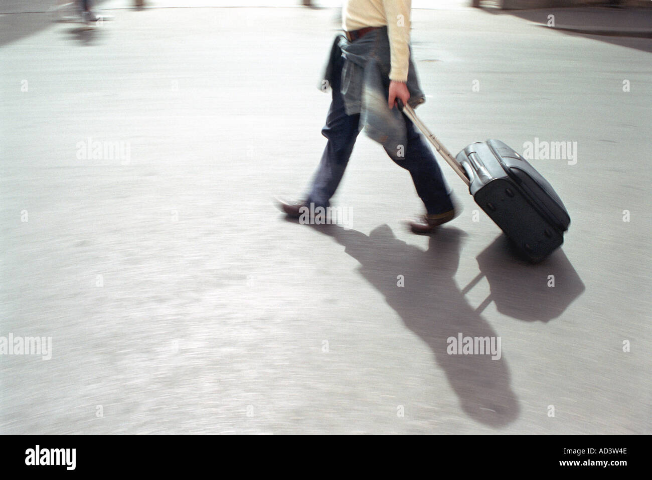 man walking with trolley suitcase blurred Stock Photo - Alamy