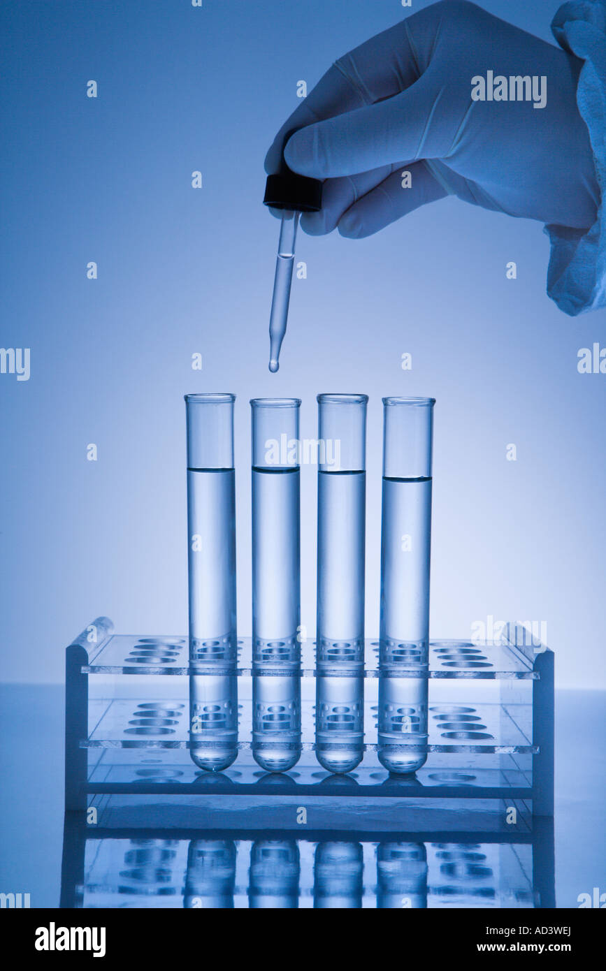 Hand holding dropper over test tubes Stock Photo - Alamy