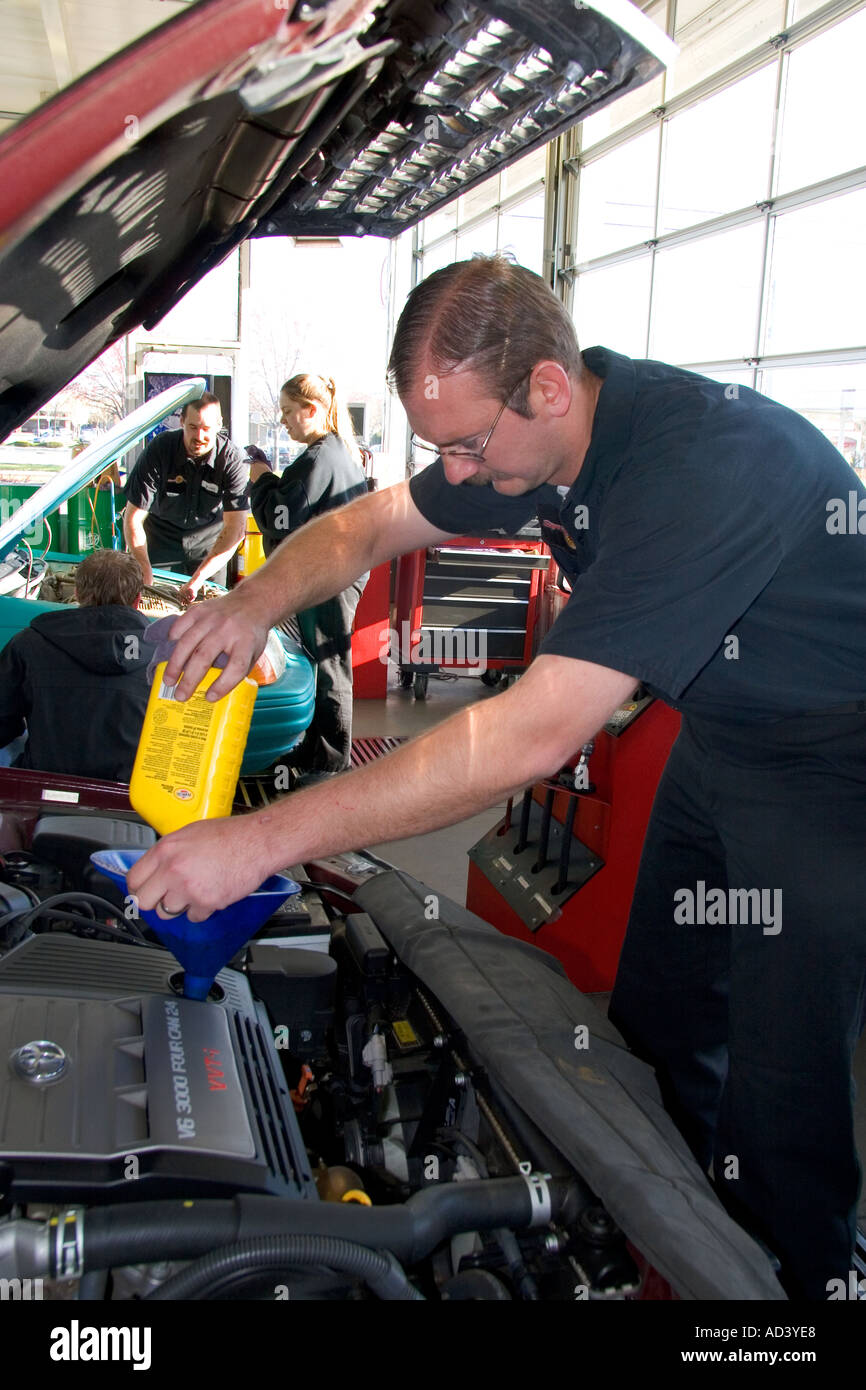 Auto mechanic adding oil in a car engine Stock Photo - Alamy