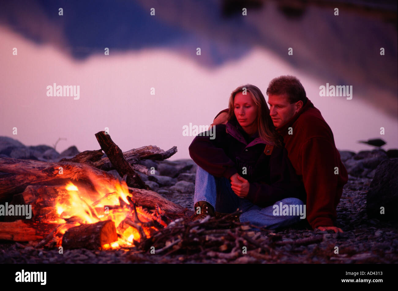 Couple by lakeside campfire at dusk Location Lake Mavora New Zealand ...