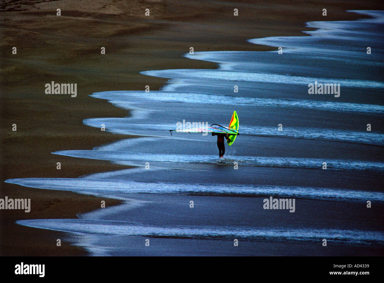 Windsurfer walking on beach mood wave patterns Stock Photo - Alamy