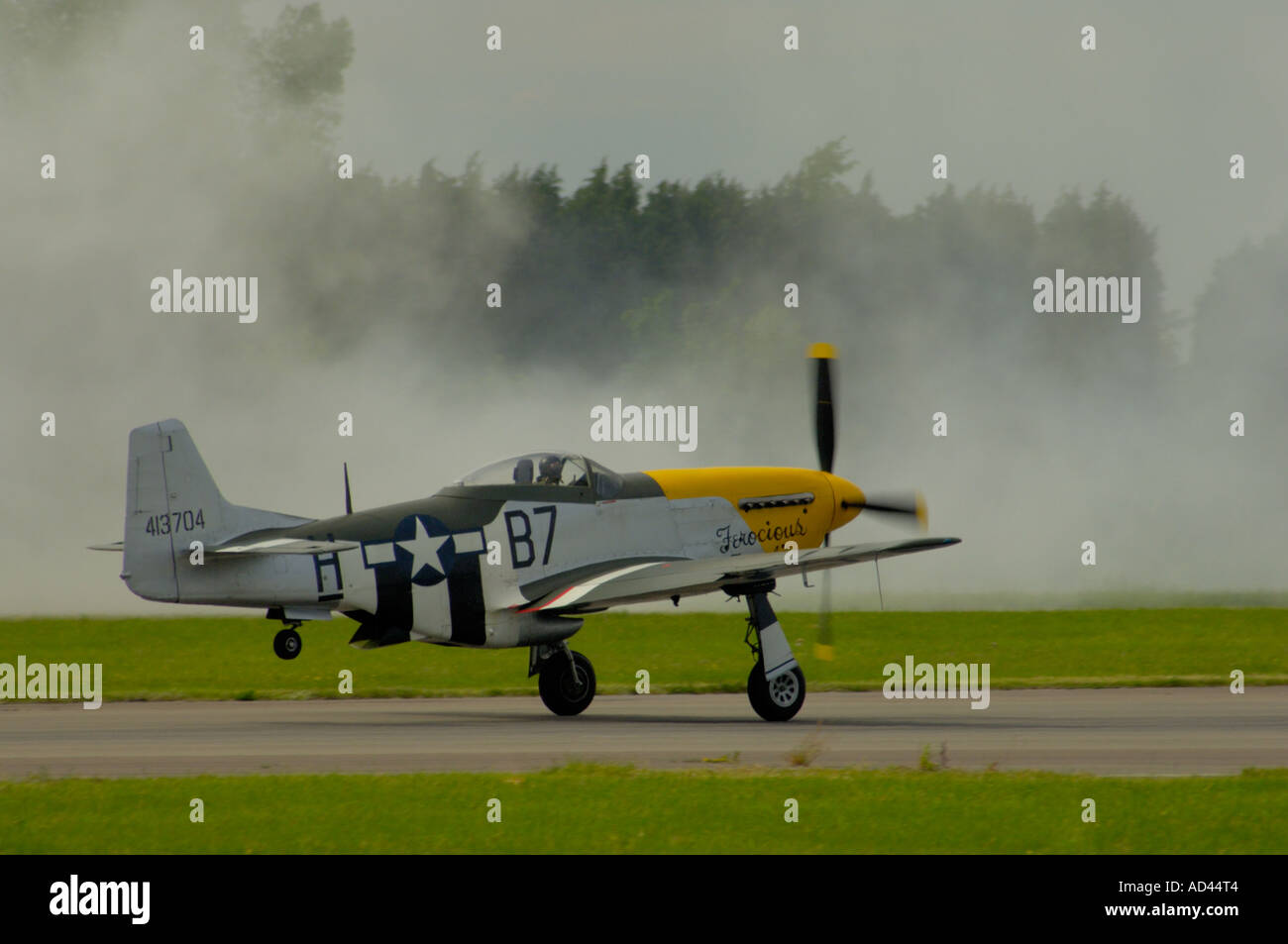 An American WW2 Mustang fighter taking off on a smoke-covered runway ...