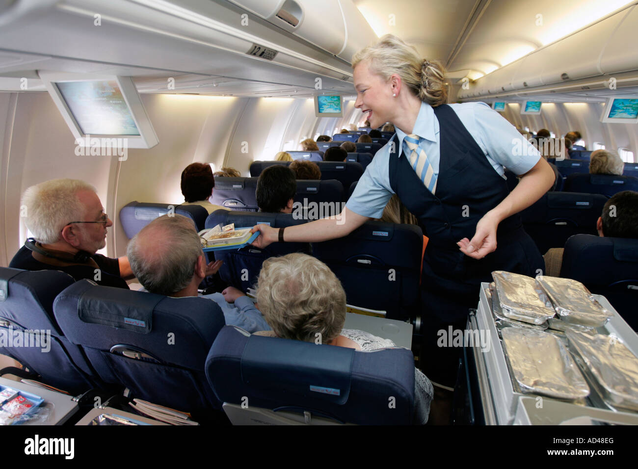 Flight attendant serving in the cabin of an aeroplane Stock Photo - Alamy