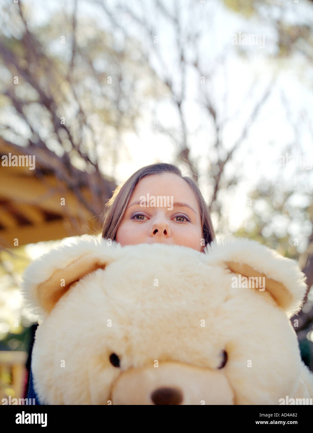 Young female model hiding behind a large plush tedy bear with only top ...