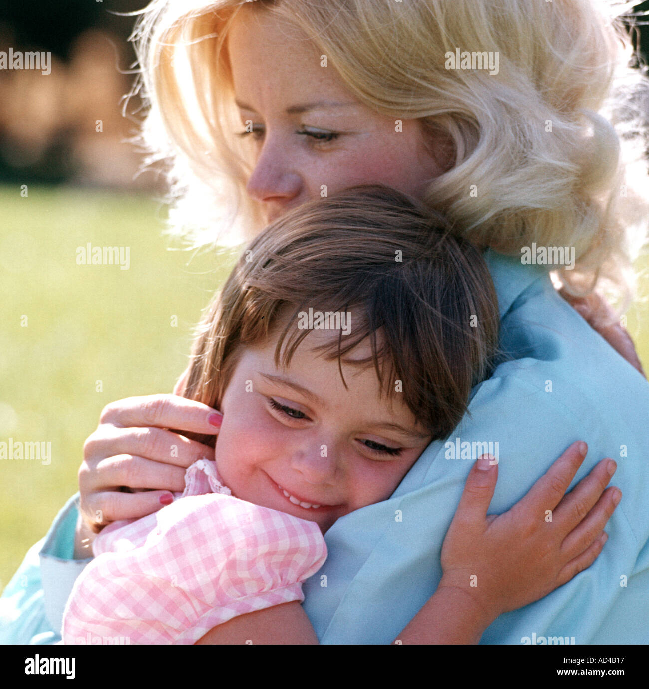 mother cuddles her small daughter while relaxing in a park Stock Photo ...
