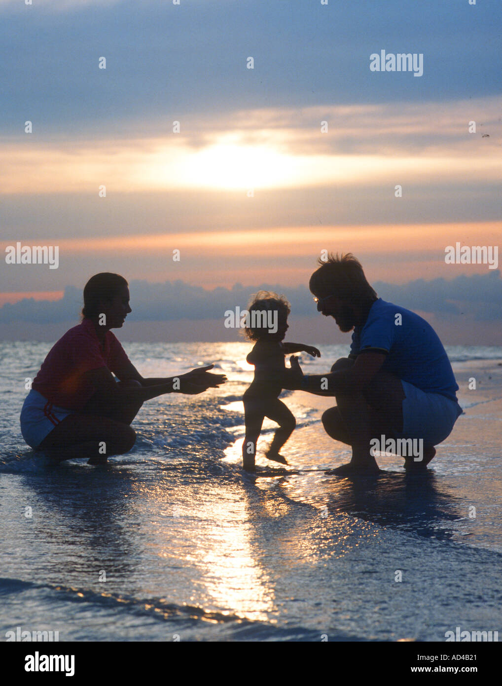 family of three playing on beach at sunset Stock Photo - Alamy