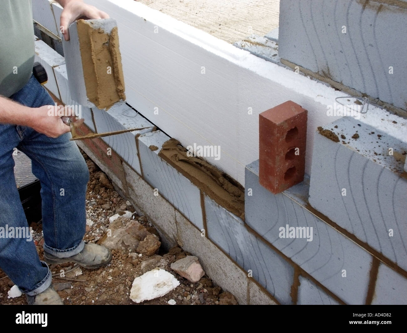 Essex house building site close up of bricklayer using trowel to lay ...