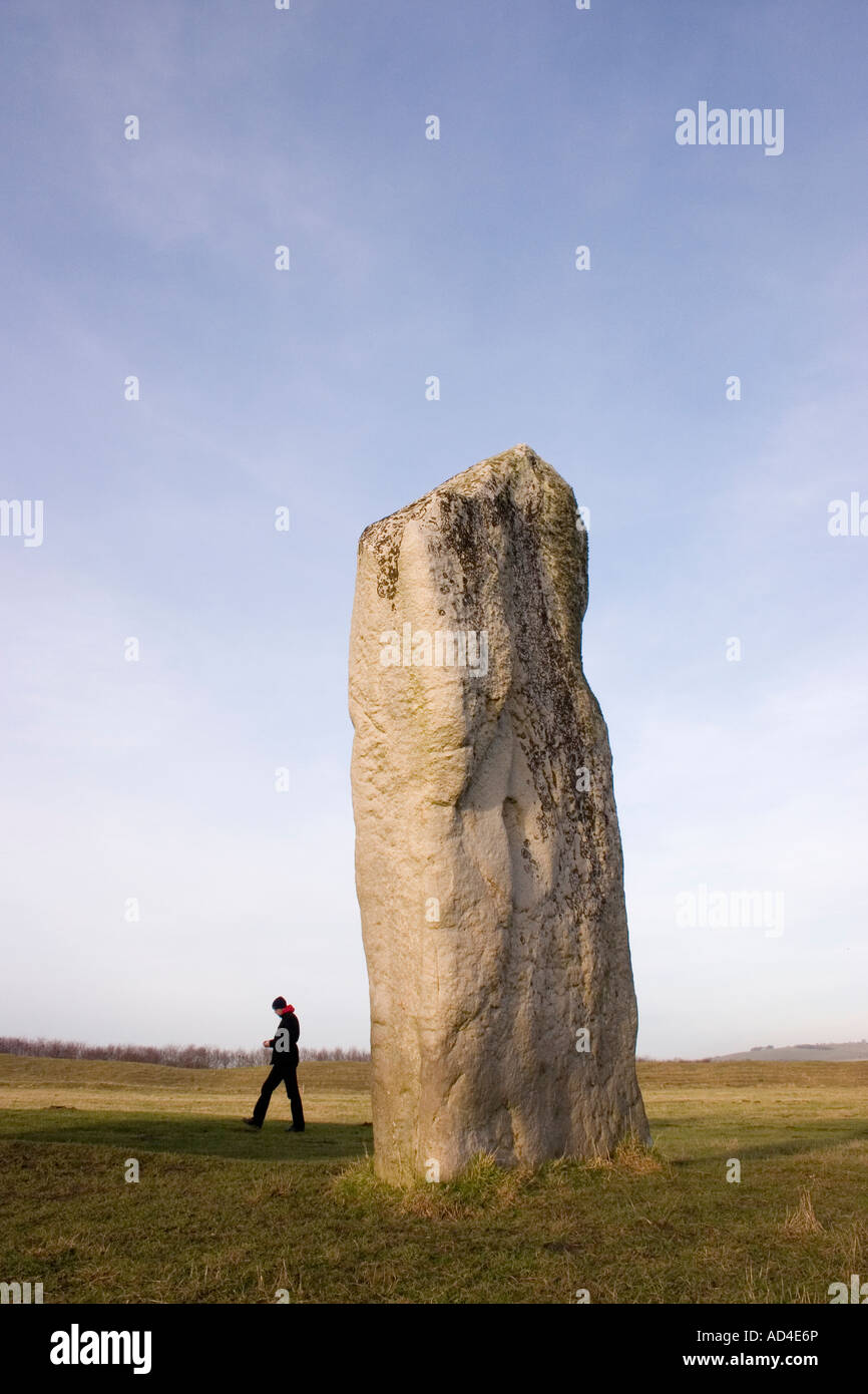 Man walking past tall single stone at Avebury Stone Circle in Wiltshire ...