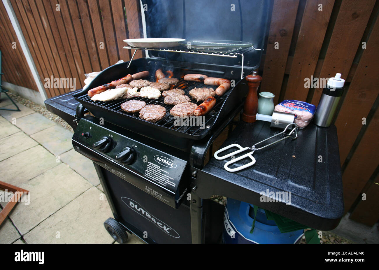 Various meats being cooked on a gas powered barbecue Stock Photo - Alamy