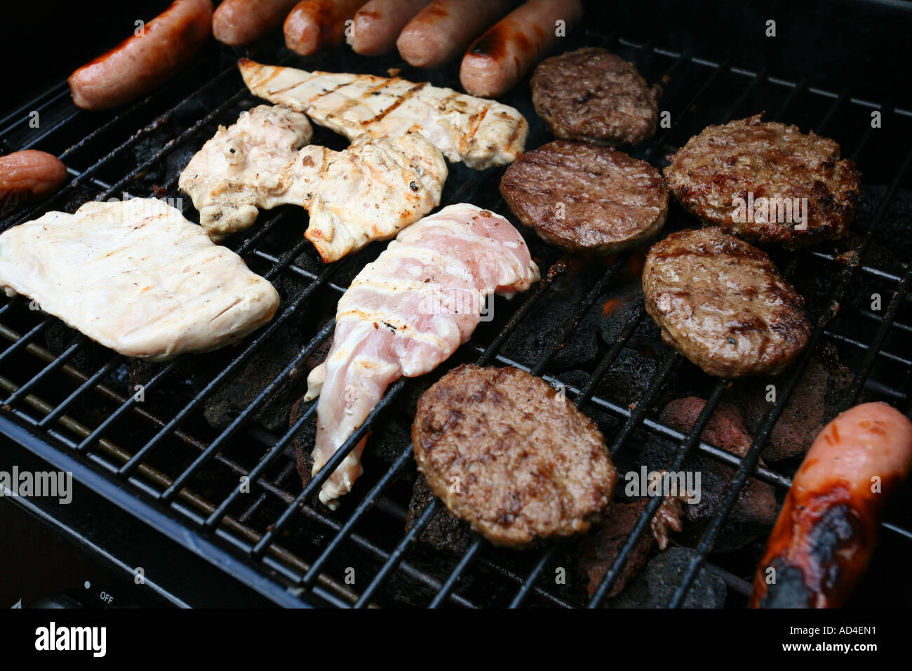 Various meats being cooked on a gas powered barbecue Stock Photo - Alamy