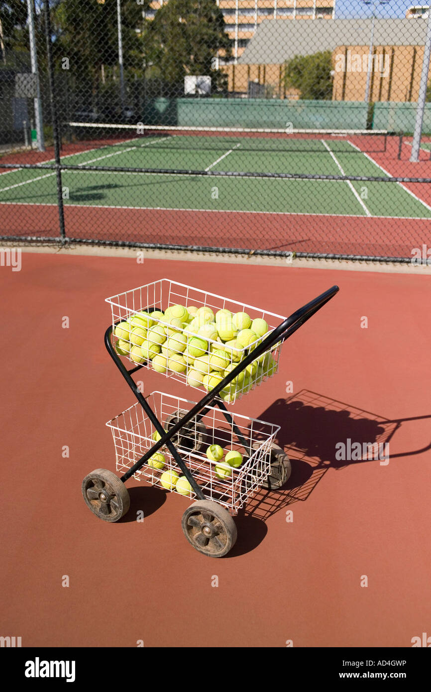 A trolley full of tennis balls at the edge of a tennis court Stock ...