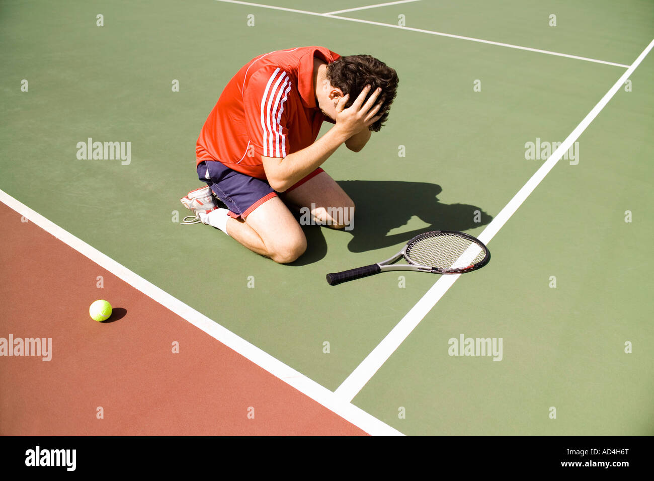 A tennis player kneeling on the court in defeat Stock Photo - Alamy