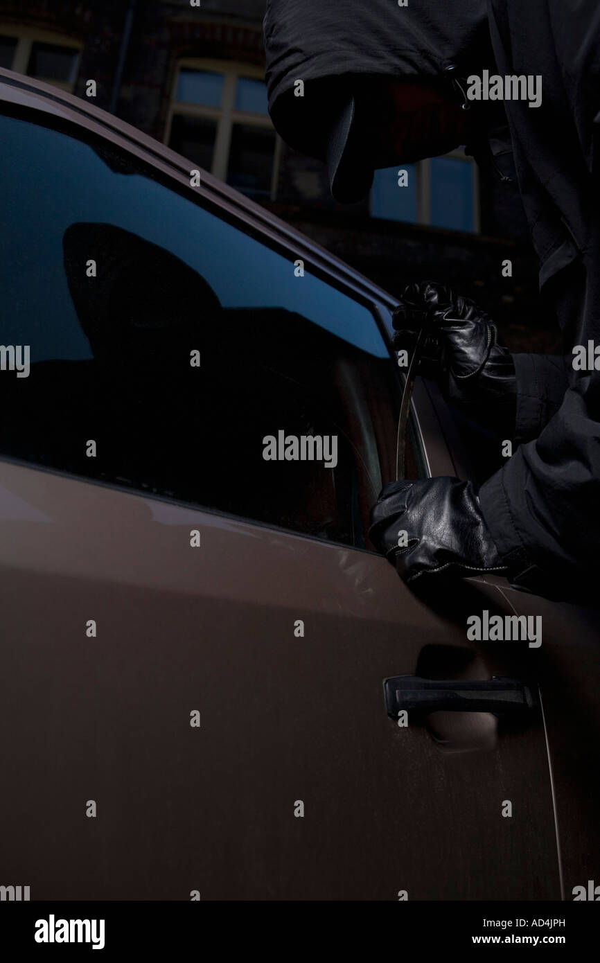 A hooded man breaking into a car Stock Photo - Alamy