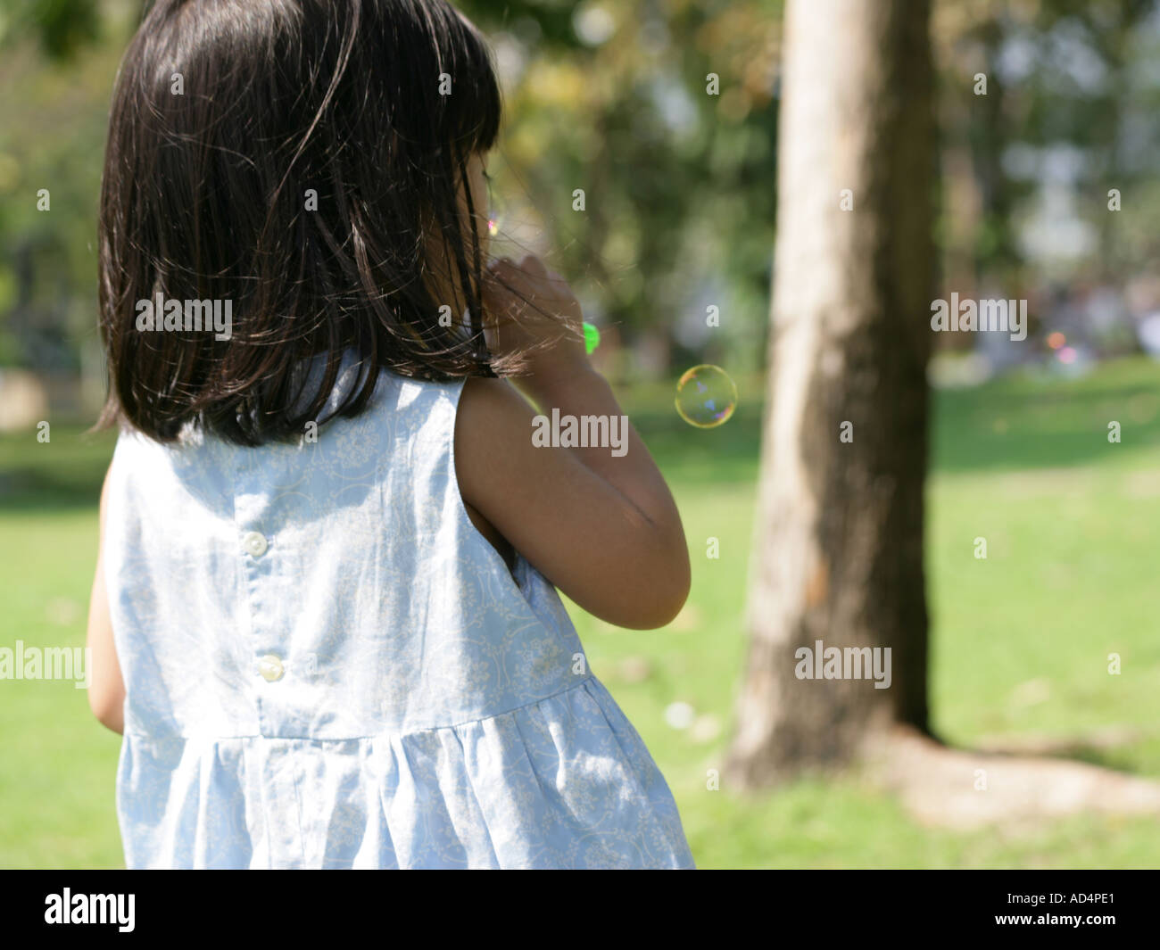 Rear view of a girl blowing bubbles with a bubble wand Stock Photo - Alamy