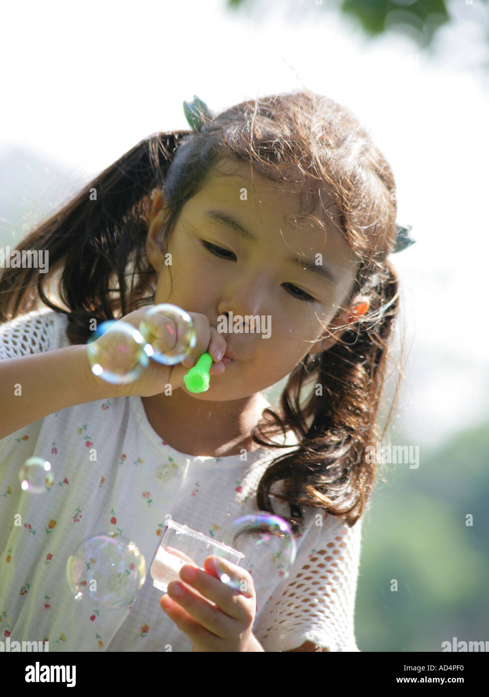 Girl blowing bubbles with a bubble wand Stock Photo - Alamy