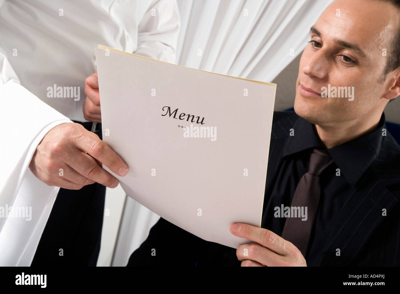 A waiter showing a man the menu Stock Photo - Alamy