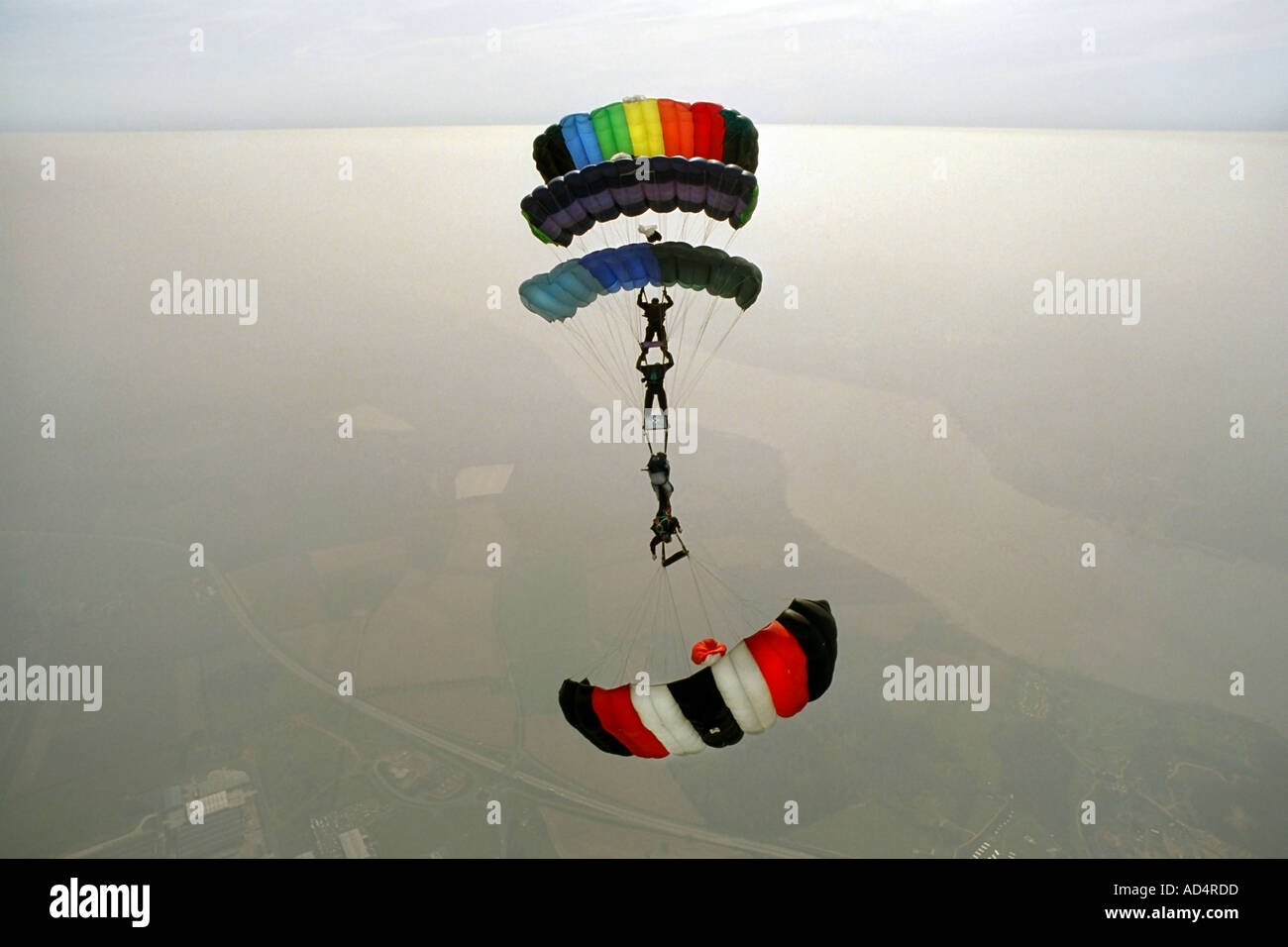 Canopy stacking over England . four Skydivers linking their parachutes ...