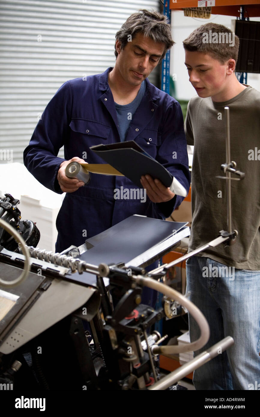 A man training a young man in a printing factory Stock Photo - Alamy