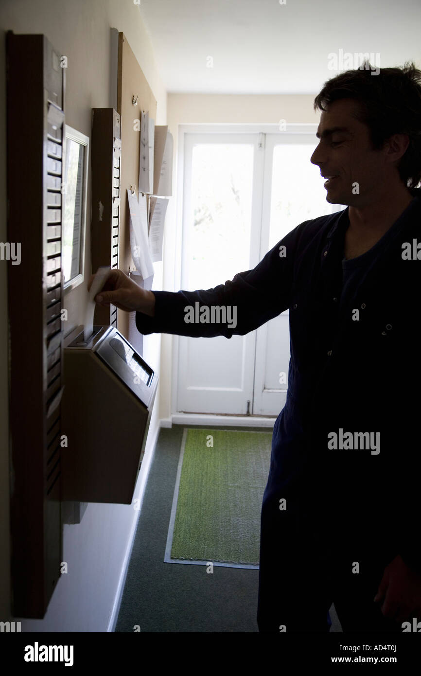 A man inserting a time card into a time clock Stock Photo - Alamy