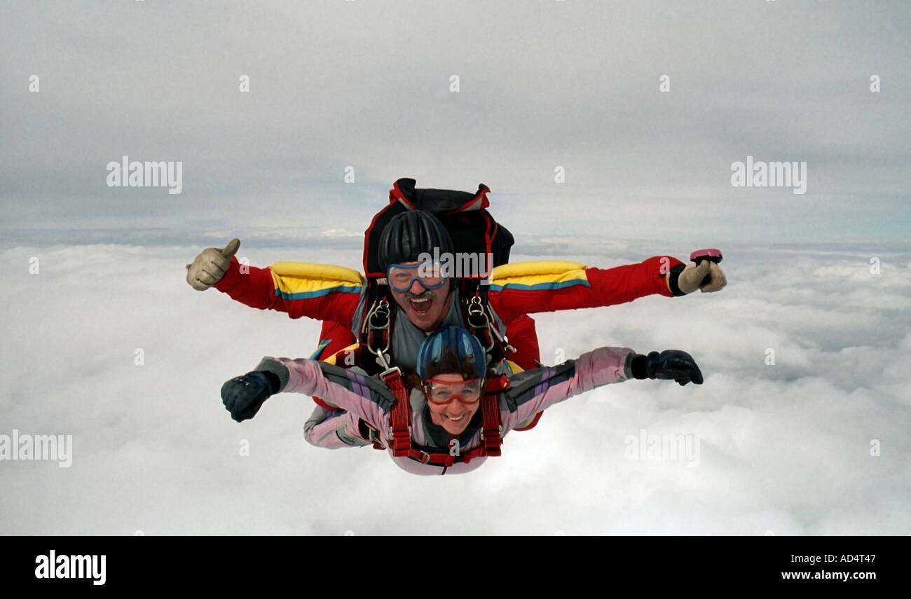 A Tandem skydive couple smile and give the thumbs up while falling at ...