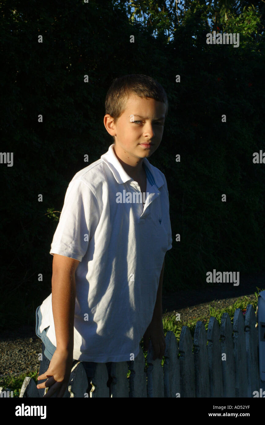 Boy looking over white picket fence Stock Photo - Alamy