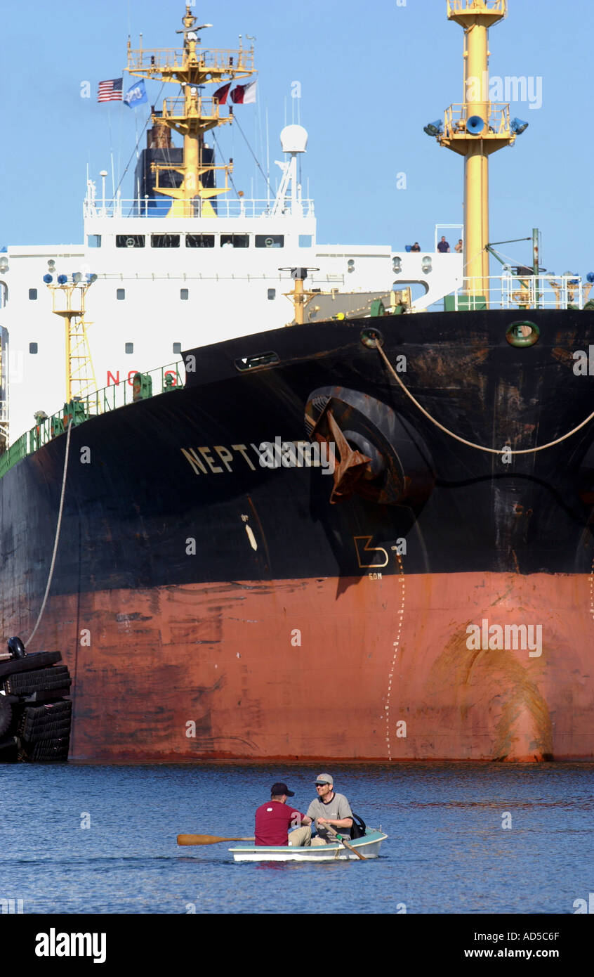 Small dingy large tanker Stock Photo - Alamy