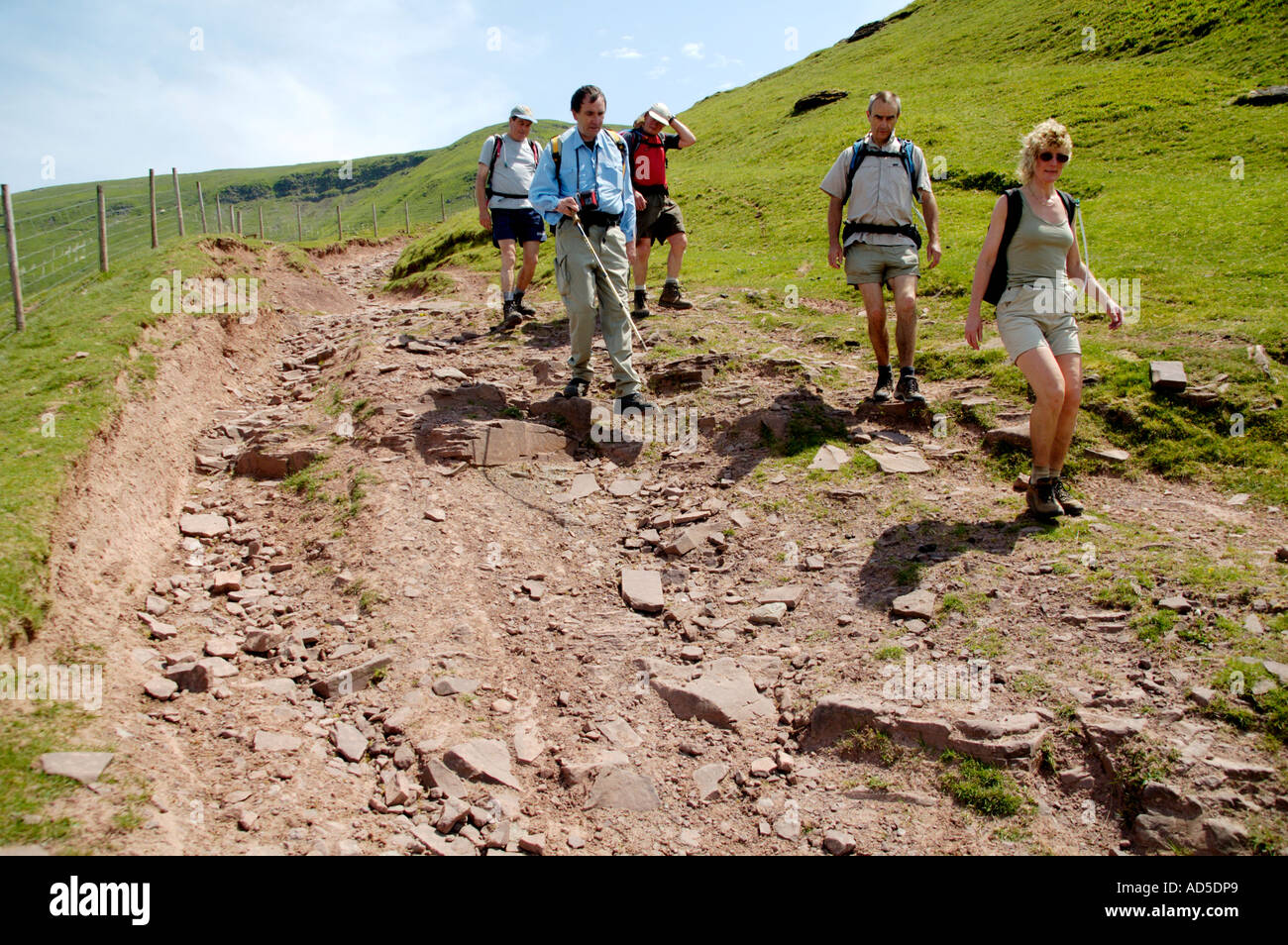 Guided walking group heading down rocky byway at Rhiw Cwnstab in the ...