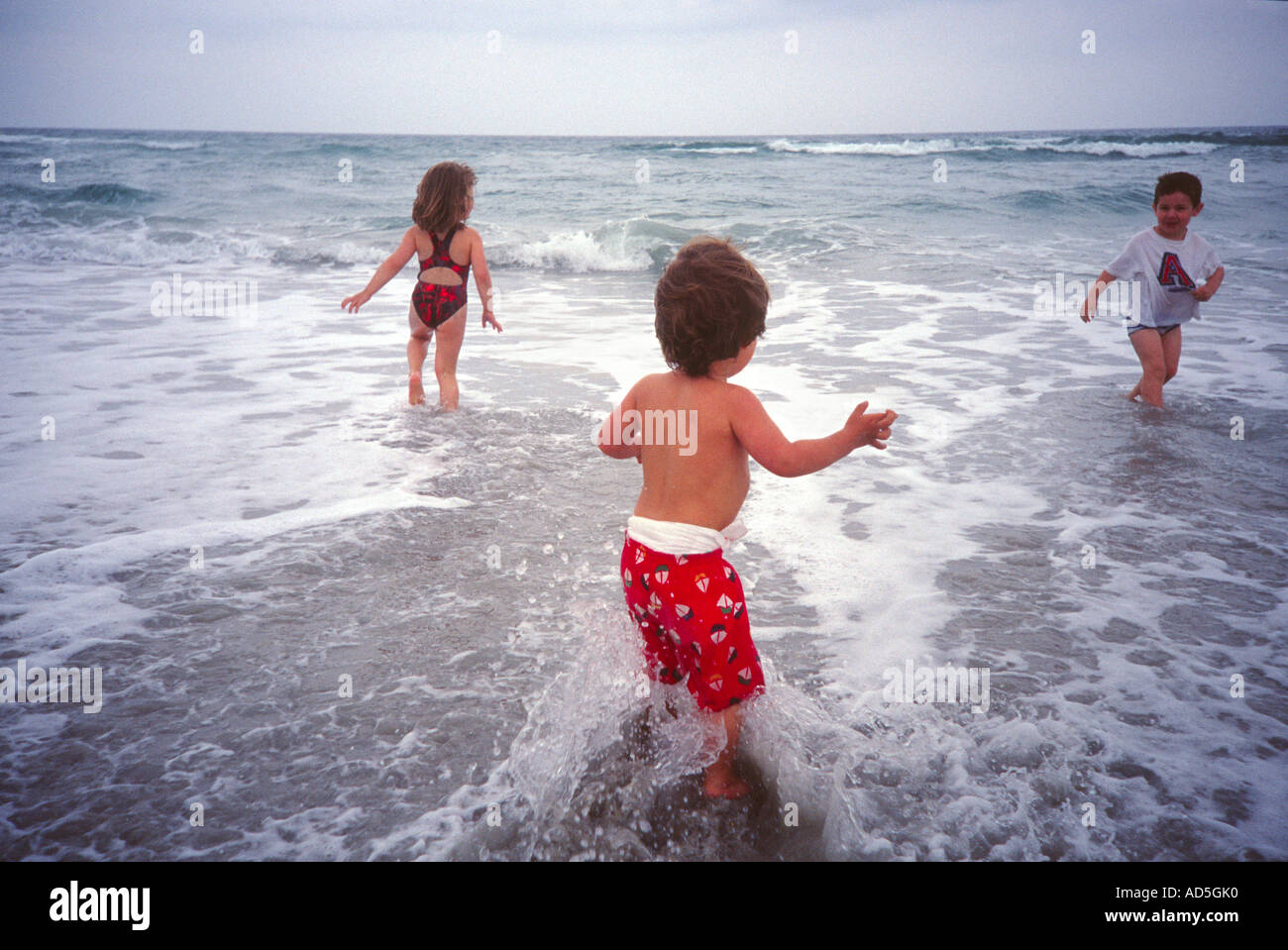 kids running into the waves at the ocean Stock Photo - Alamy