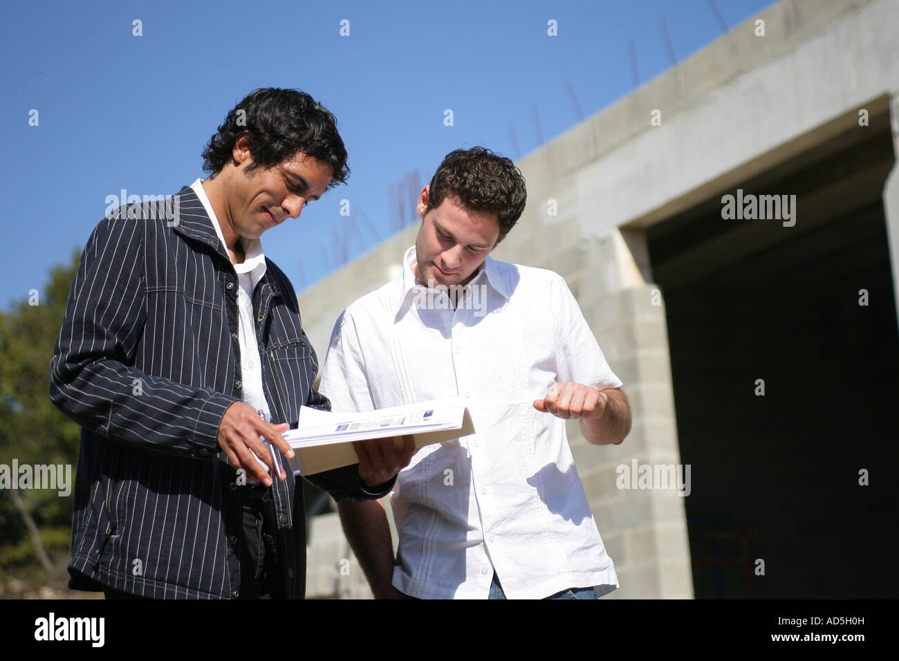Young man with estate agent on building site Stock Photo - Alamy