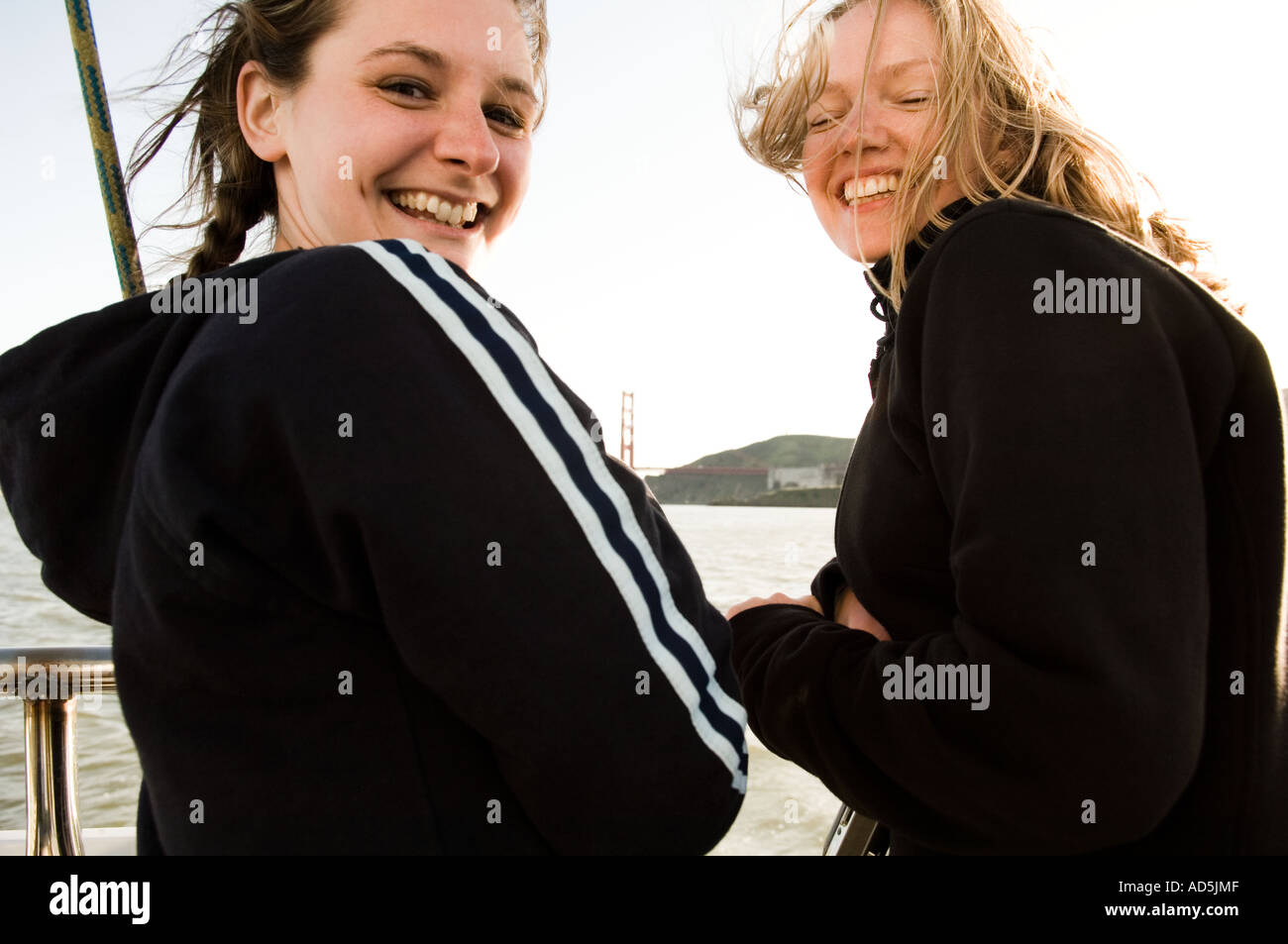 Two girls 20s on the front of sail boat on San Francisco harbor with ...