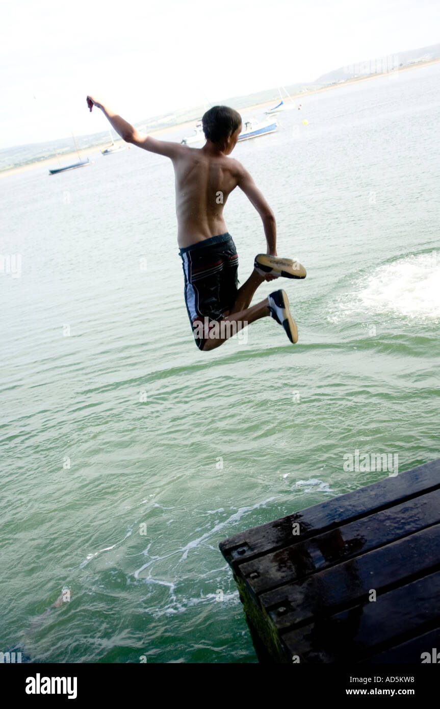 Young boy leaping into the sea from the jetty at Aberdyfi Aberdovey ...