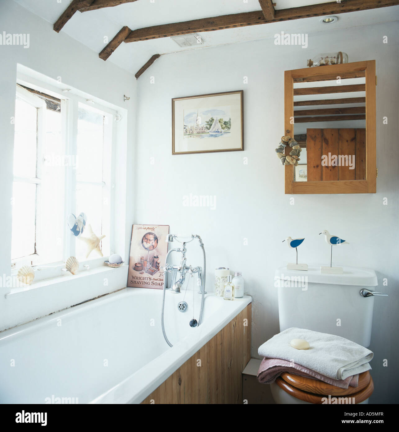 Wooden mirror above toilet in white bathroom with panelled bath Stock ...