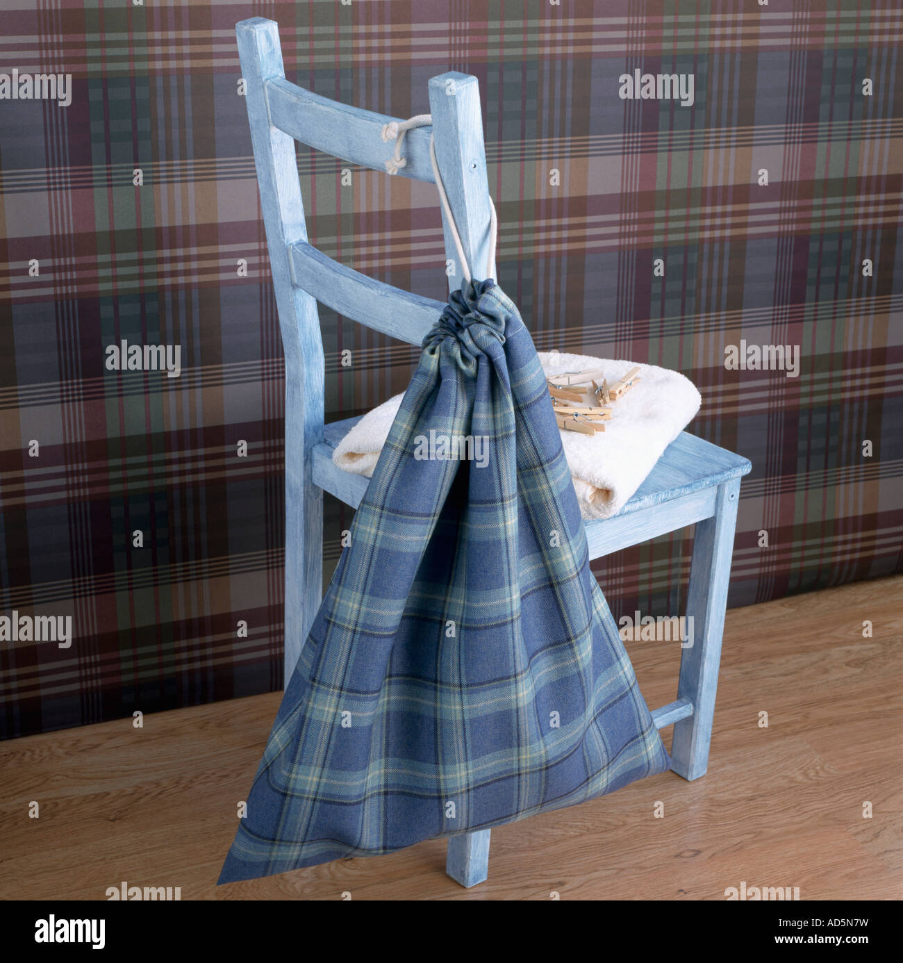 Blue checked laundry bag on pastel blue painted wooden chair against ...