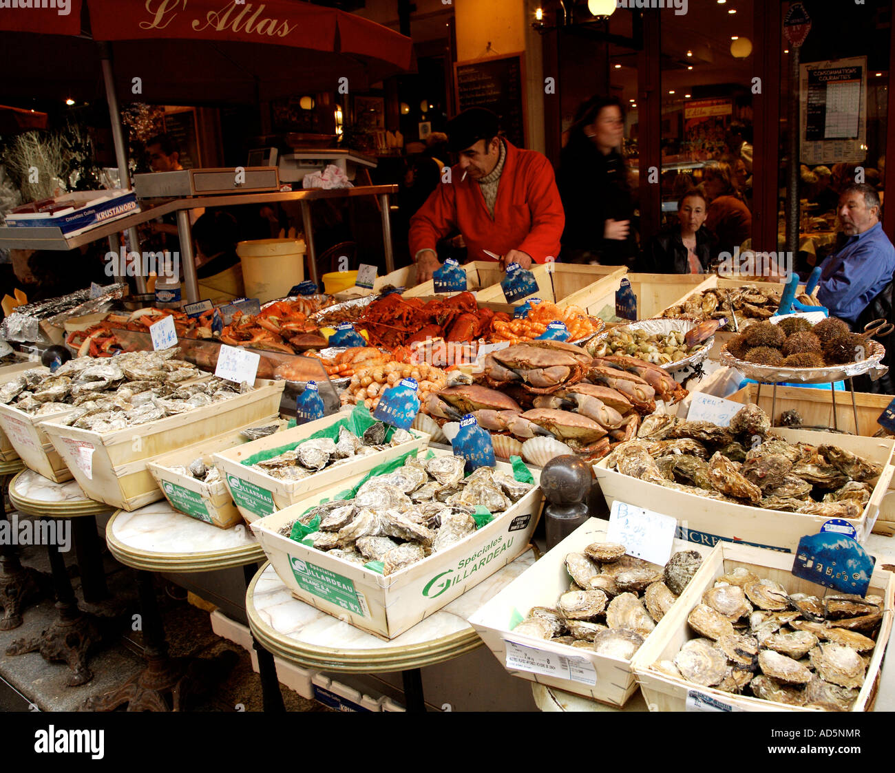Stall holder arranging shellfish in display boxes on stall in French ...