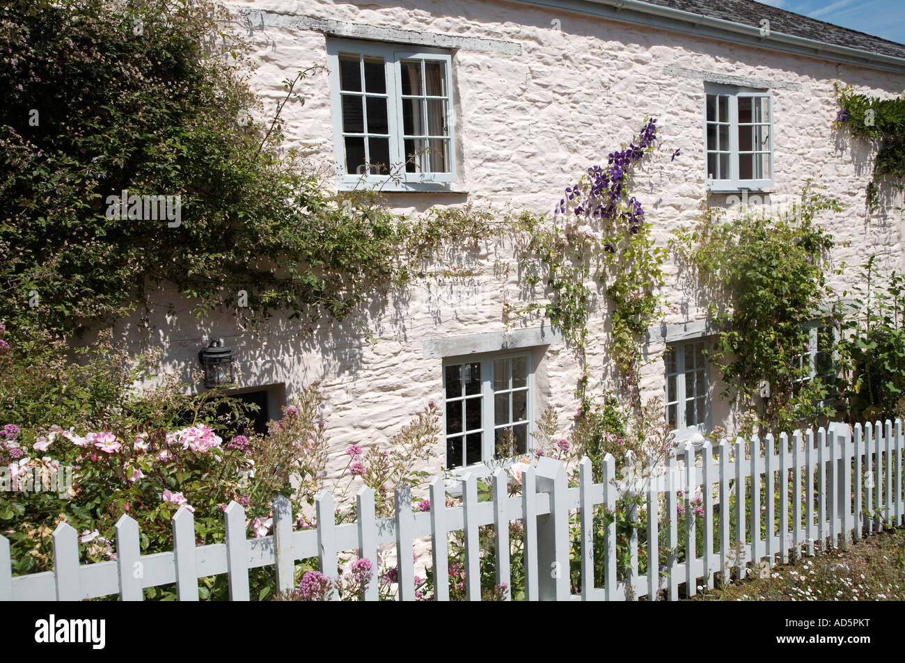 Traditional white English stone cottage with pale grey picket fence ...