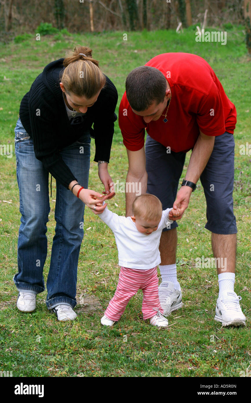 Parents helping their child to walk Stock Photo - Alamy