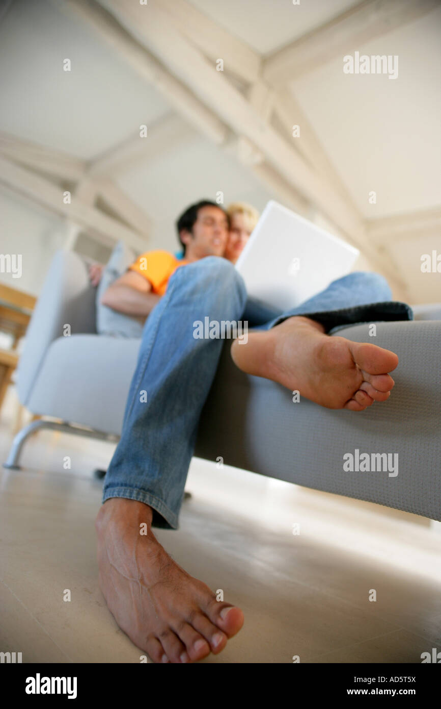 Couple laying on a couch with laptop computer Stock Photo - Alamy