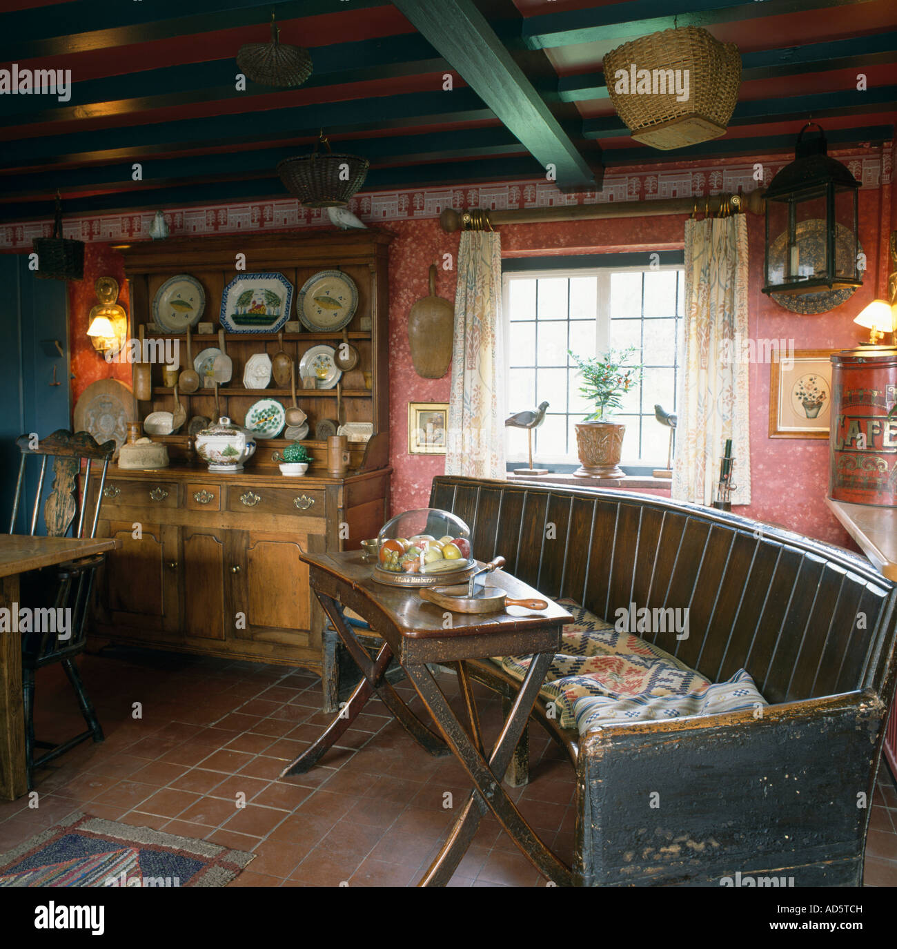 Antique settle and table in red cottage diningroom Stock Photo - Alamy