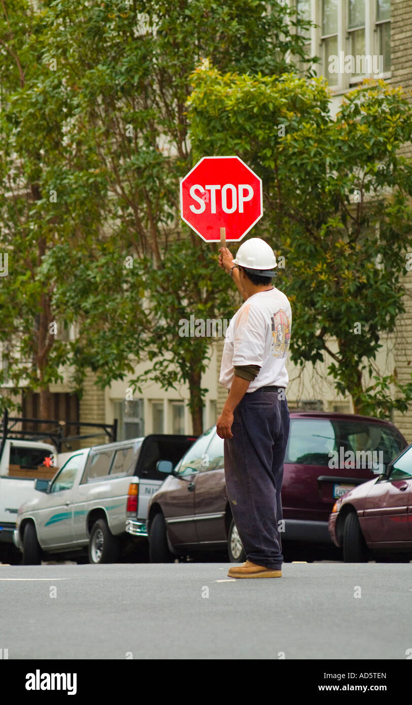 Construction Worker Holding Stop Sign On City Street Stock
