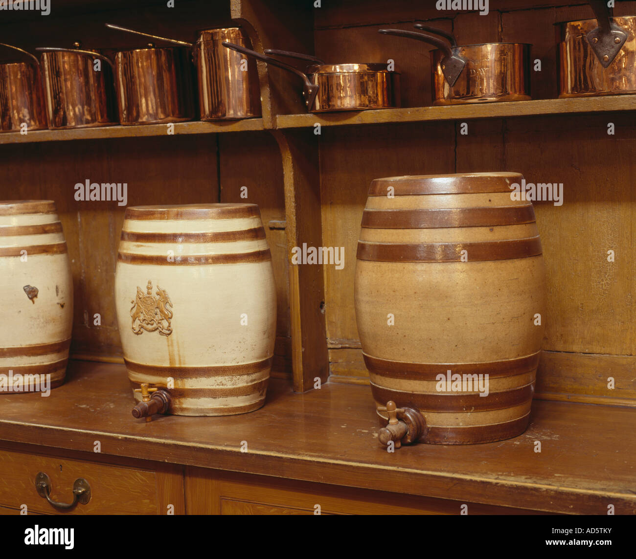 Earthenware beer kegs below copper pans on shelf Stock Photo - Alamy