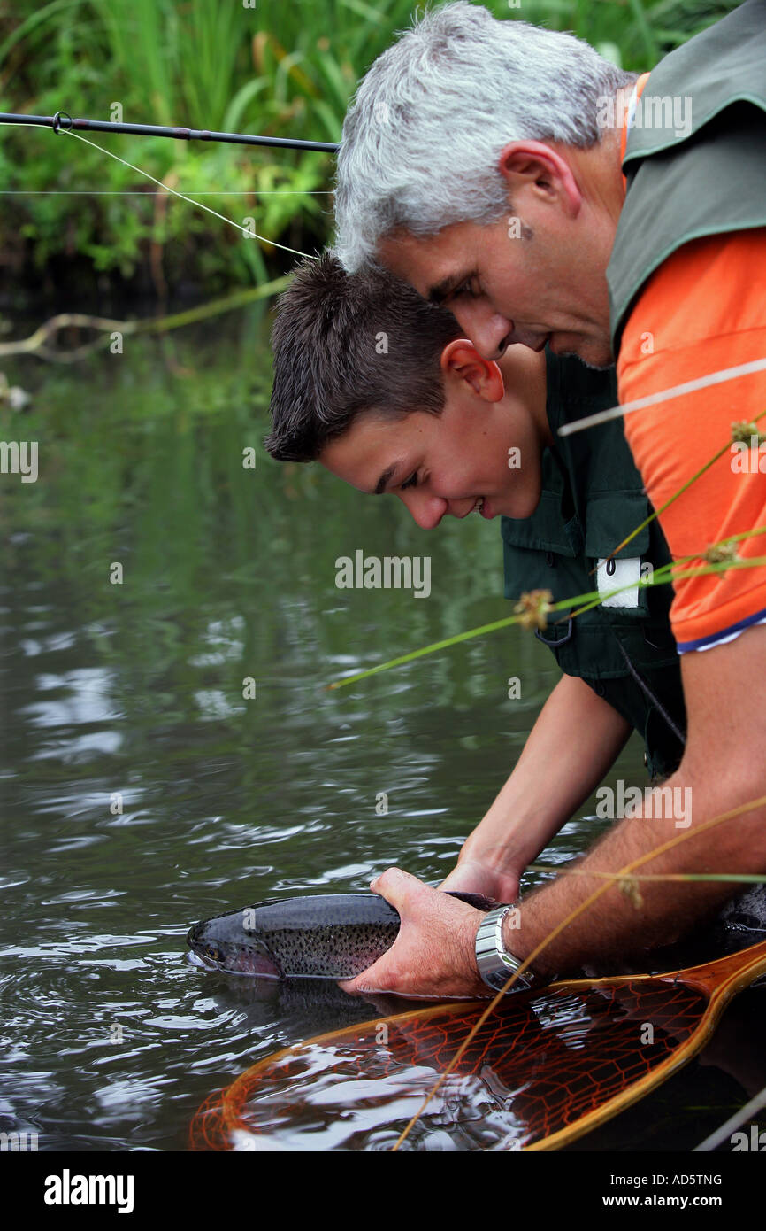 Man and boy catching a fish with a net Stock Photo - Alamy