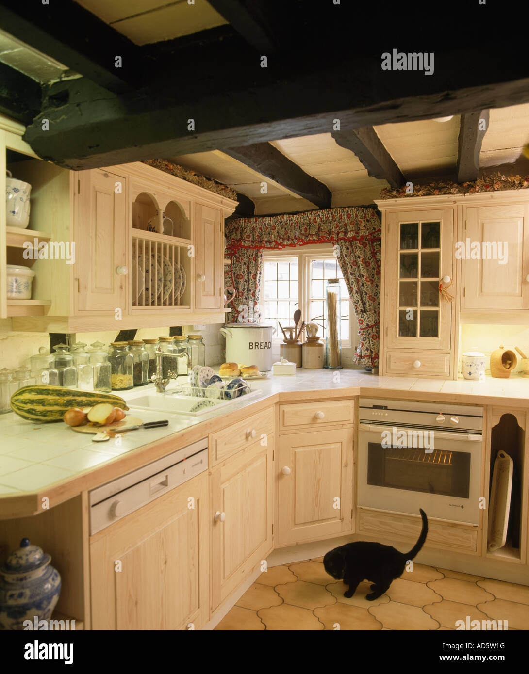 Corner of cream cottage kitchen with built in dishwasher and oven and ...