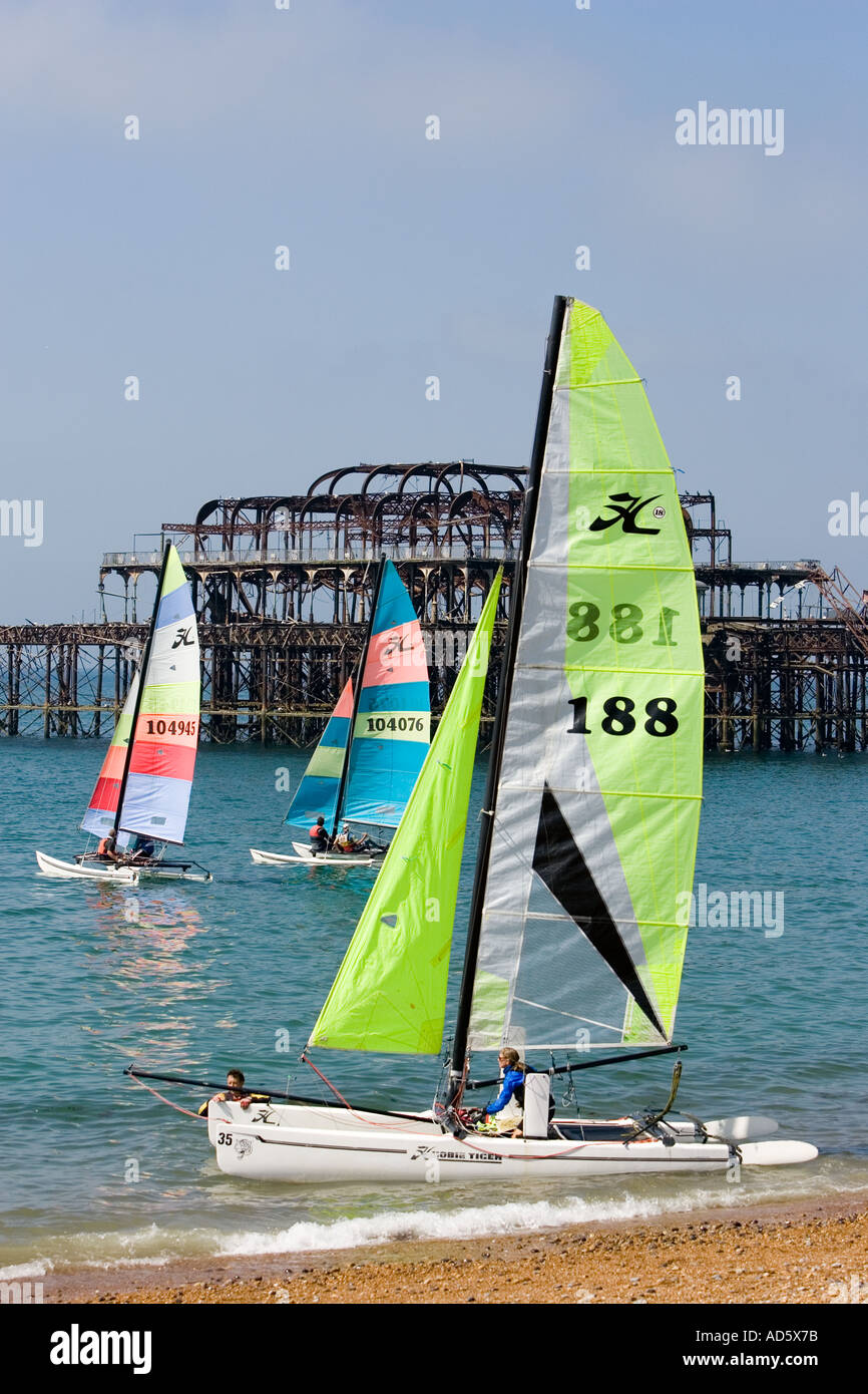 Three sailing boats launch into the sea off the beach in front of ...