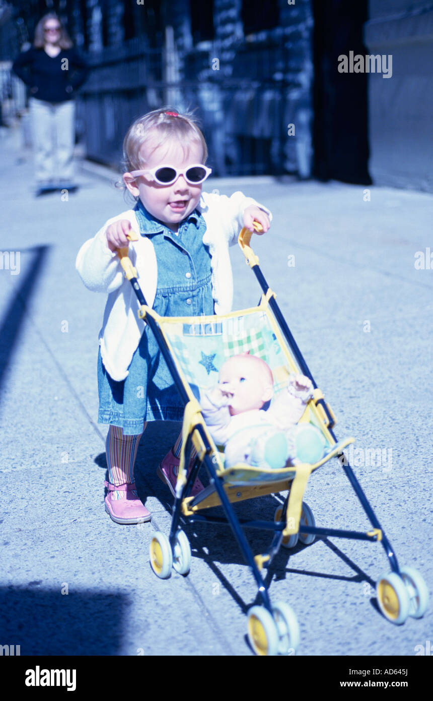Toddler girl pushing stroller with doll Stock Photo - Alamy