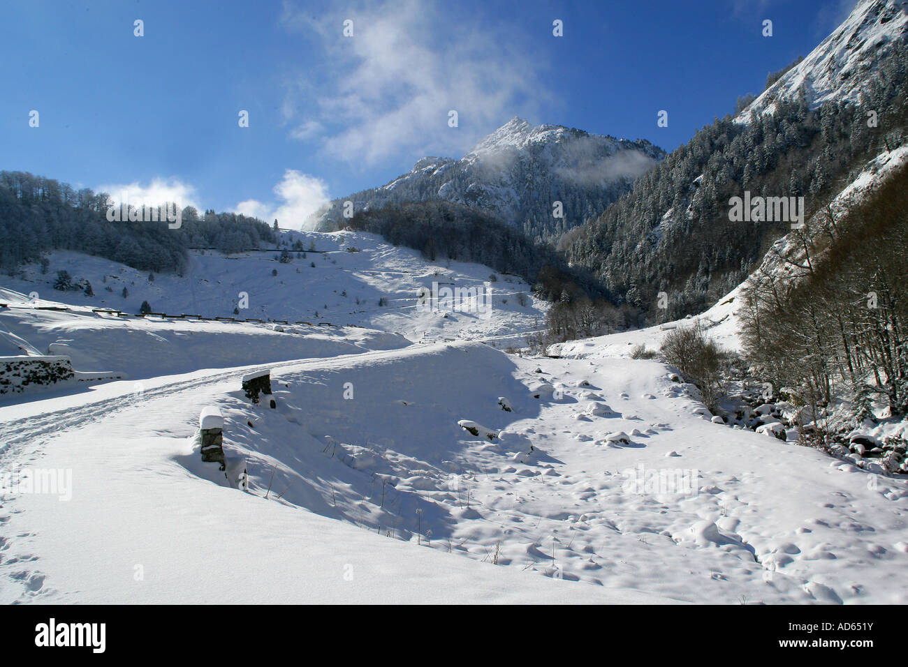 snow covered track or road crossing a tree covered mountain massif, a ...