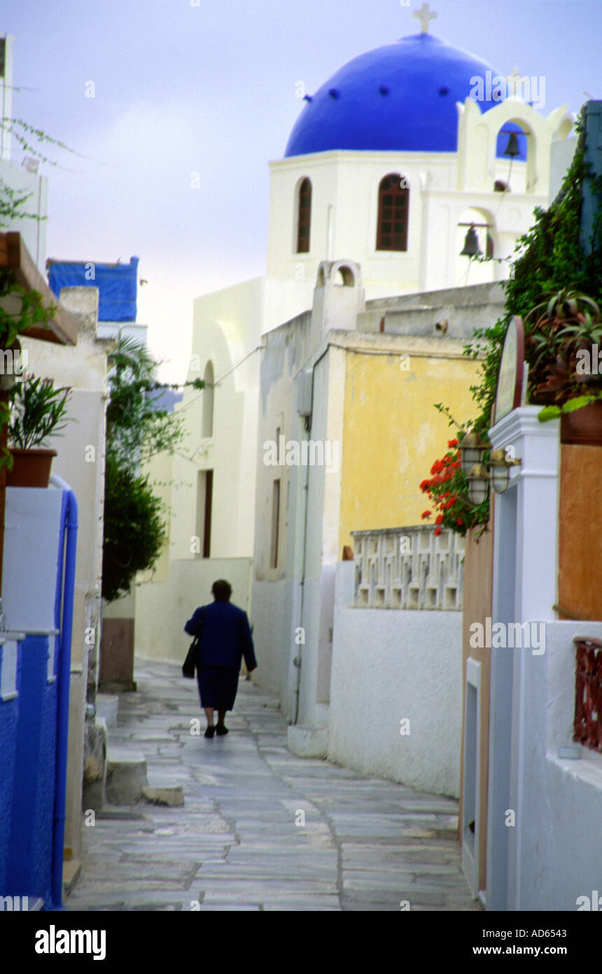 Greek woman taking a morning stroll on the marble paved paths of Oia on ...