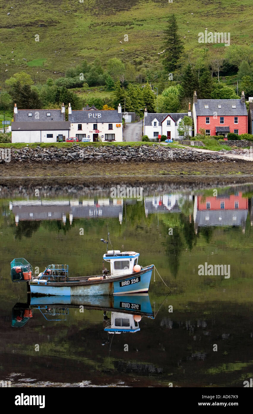 Coloured painted houses and fishing boat reflected in the water next to ...