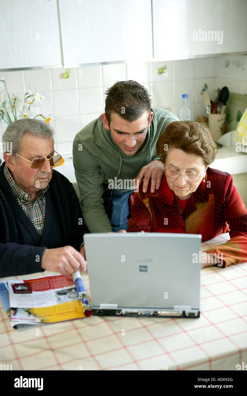elderly people at home with laptop computer and young man helping them ...