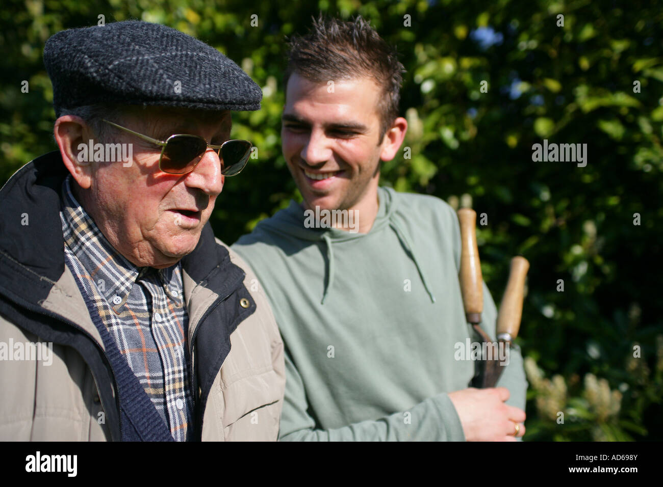 young man helping old man in the garden Stock Photo - Alamy